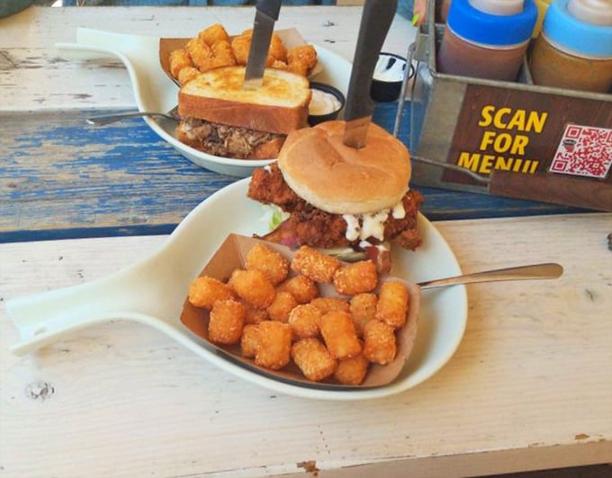 Comfort food evolution: crispy tater tots supporting a sandwich that requires both hands and possibly a signed waiver. Worth every delicious calorie.