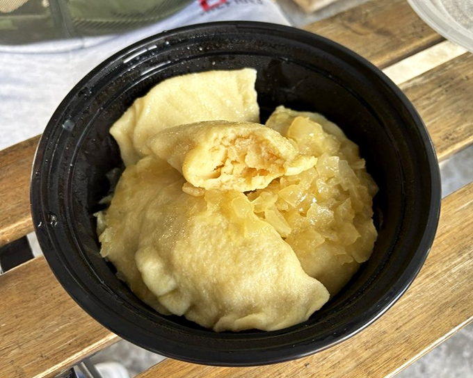 Buttery pierogies nestled in a take-out container&mdash;the ultimate "treat yourself" moment waiting to happen at home.