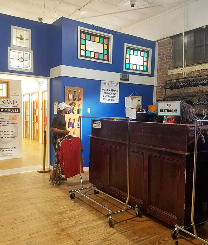 The vintage wooden counter, backed by stained glass windows, serves as command central for this carefully curated fashion universe.