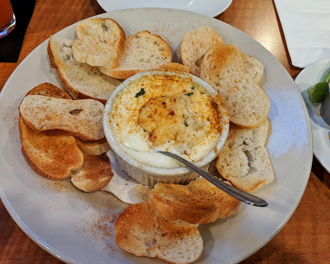 This crab dip isn't just served—it's presented, surrounded by toasted bread like courtiers attending to royalty. Dipping required, sharing optional.
