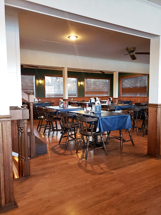 Blue tablecloths and wooden chairs create an atmosphere of casual elegance. The ship's wheel reminds you this isn't just any restaurant.