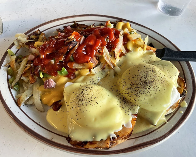 Benedict done right: perfectly poached eggs nestled on English muffins, draped in hollandaise and surrounded by hash browns. Breakfast architecture that would make Michelangelo weep.