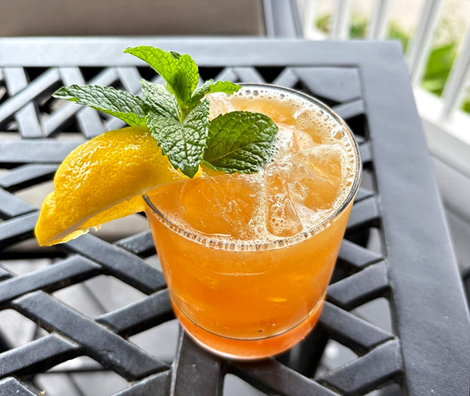 A refreshing cocktail garnished with fresh mint and citrus, sitting pretty on the patio. Sunshine in a glass, with just enough kick to make the afternoon interesting.