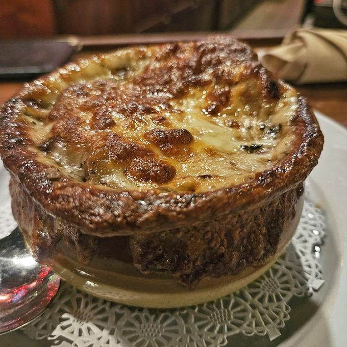 French onion soup with a cheese cap that stretches to infinity. Beneath that glorious dome lies a broth so rich it could buy a small island.