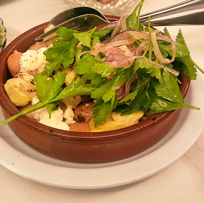 The Gigante Beans dish is Mediterranean comfort in a terra cotta bowl – creamy beans, fresh herbs, and the kind of simple preparation that requires serious skill.