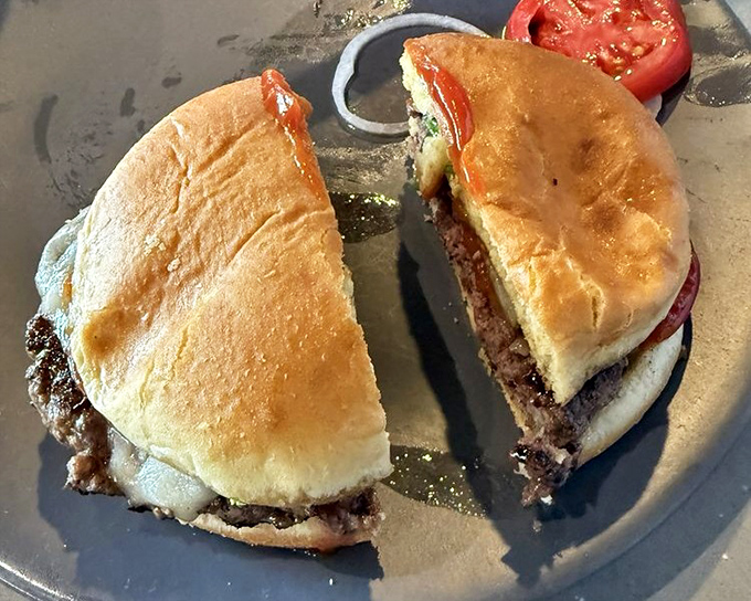 A burger cut in half not to check doneness (they know better), but to let you admire the perfect medium-rare interior like a geological cross-section of deliciousness.