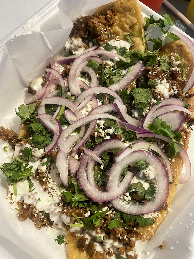 The huarache – a sandal-shaped masa canvas painted with layers of beans, meat, crema, and fresh toppings – edible art at its finest.