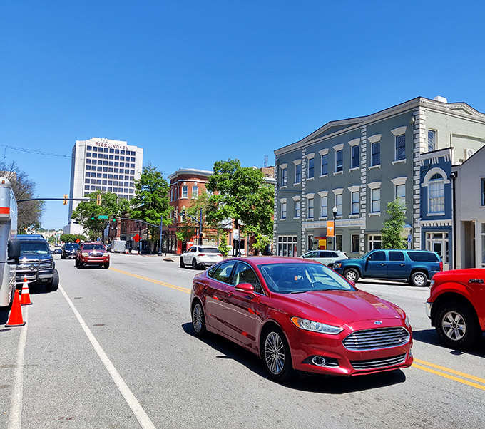 Main Street traffic flows past historic facades where modern life meets antebellum elegance in perfect Southern harmony.