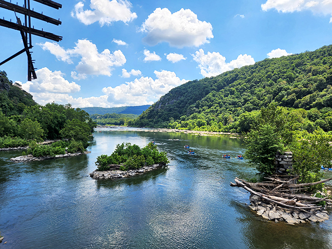 The Potomac River curves gracefully between mountain walls, with tiny kayakers adding splashes of color to nature's masterpiece.