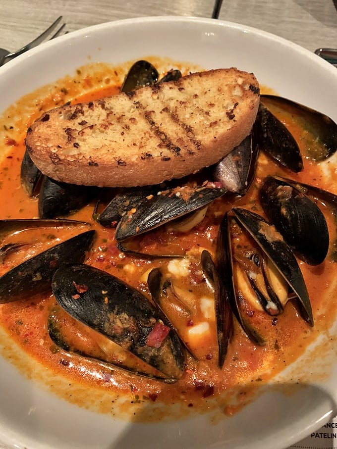 Mussels bathing in a vibrant tomato broth with a slice of grilled bread perched on top. This dish isn't just eaten&mdash;it's experienced, with each shell hiding a treasure of flavor.