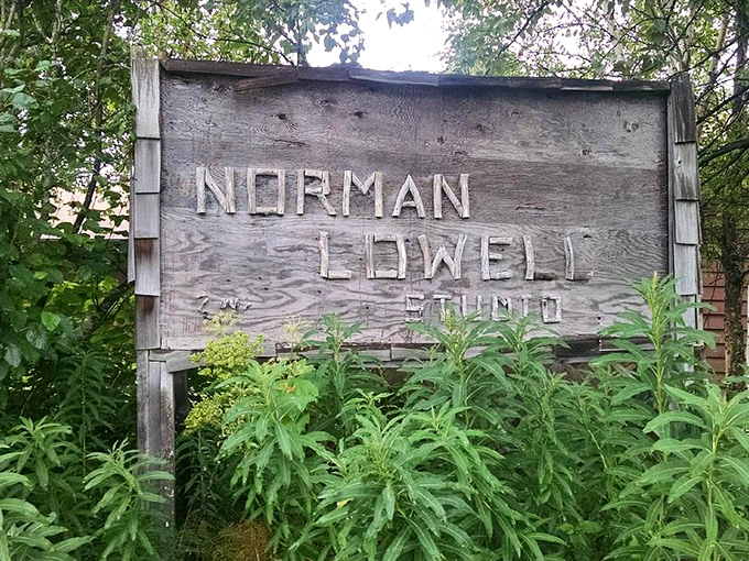 The weathered sign for Norman Lowell Studio stands as a testament to Alaska's artistic spirit thriving in the wilderness.