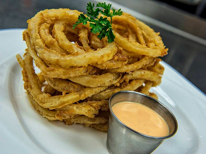 Onion rings stacked higher than your weekend ambitions, with a dipping sauce that makes sharing a true test of friendship.