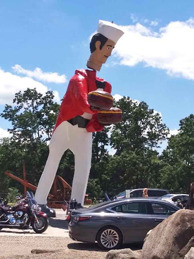 Parked vehicles provide scale to this towering figure. Even large SUVs look diminutive next to Ohio's most enthusiastic server.