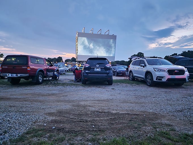 Cars align like faithful congregants before their silver screen altar, tailgates open and lawn chairs deployed for optimal viewing.