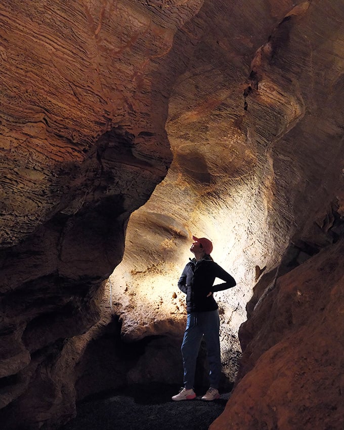 The dramatic lighting transforms ordinary rock walls into cathedral-like spaces. This visitor seems to be contemplating just how small we are in geological time.