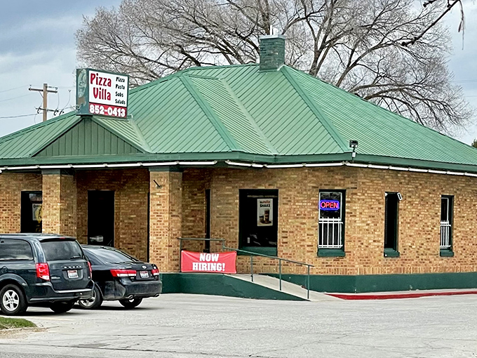 Pizza Villa's distinctive green roof shelters affordable family dinners where the conversation flows easier than your retirement savings.