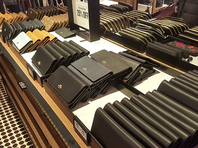 Leather wallets arranged with mathematical precision – each one waiting to be the new home for your credit card that made its purchase possible.