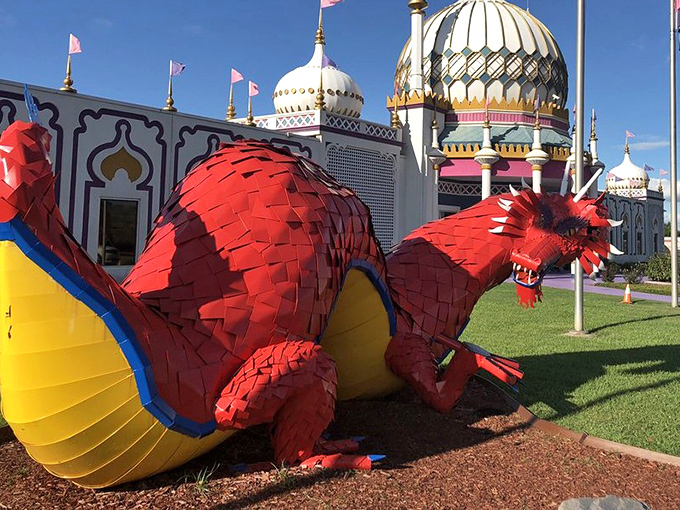 The fierce red dragon guards the palace like a mythical Texas watchdog. Its vibrant scales pop against the ornate white building behind it. 