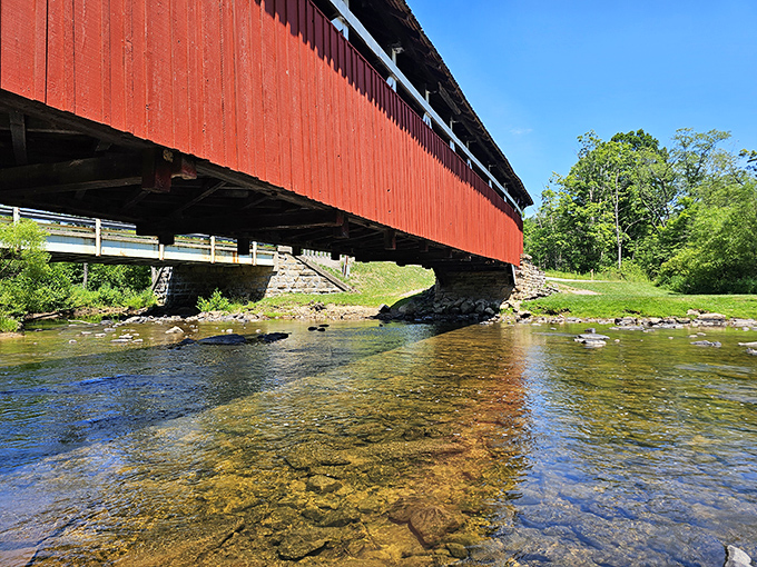 The clear waters of Laurel Hill Creek flow beneath this scarlet sentinel, reflecting centuries of travelers who've made this crossing.