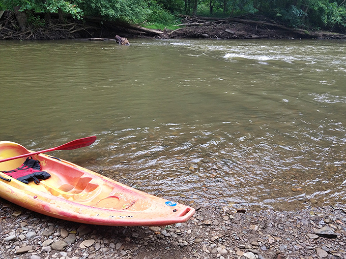 A kayak rests on muddy shores where the real adventure begins&mdash;no experience necessary, just courage and a sense of humor.