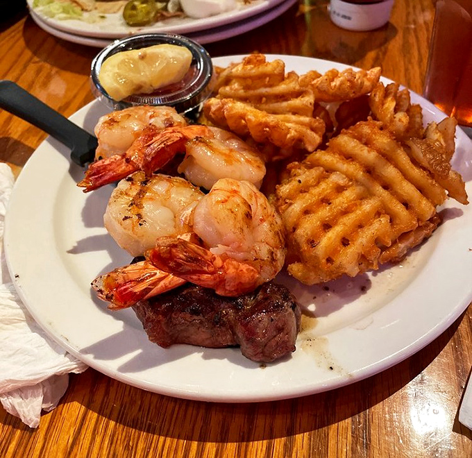 Surf meets turf in this harmonious plate duet &ndash; plump grilled shrimp and a juicy steak sharing the spotlight with those addictive waffle fries.