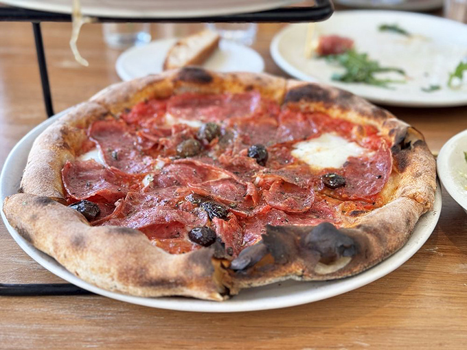 Thin-sliced cured meat lounges on a perfectly charred crust like it's sunbathing on Italian shores—a vacation for your taste buds.