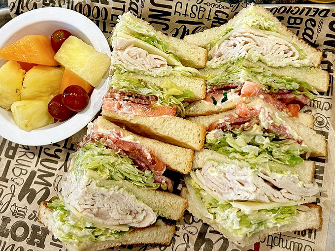 The club sandwich towers with layers of turkey, bacon, and all the fixings, served alongside fresh fruit that balances things.