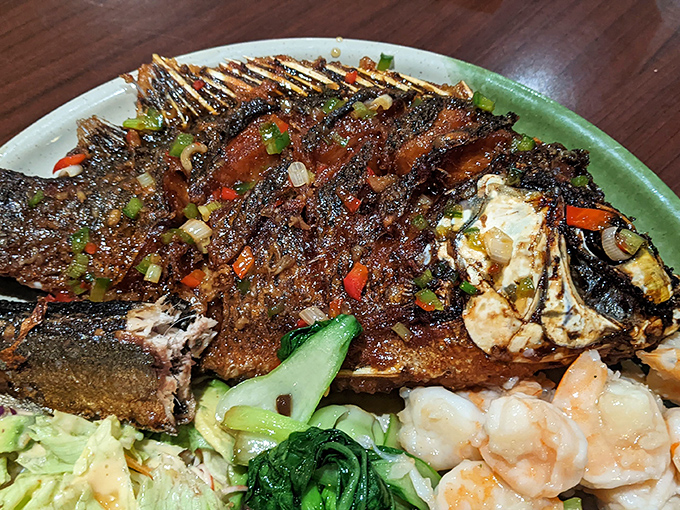 This whole tilapia is having its glamour moment, dressed to impress with colorful vegetables and enough garnish to make a statement.