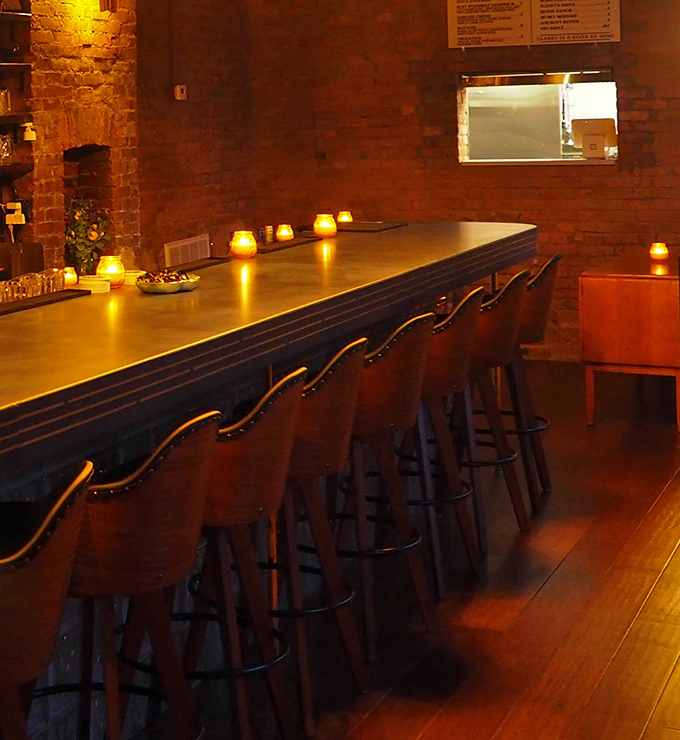 The bar at dusk&mdash;where candles flicker, conversations flow, and strangers become friends over shared plates.