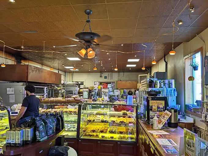 Behind the counter, pastry cases gleam like jewelry displays, except these gems disappear with delighted customers rather than lasting forever.