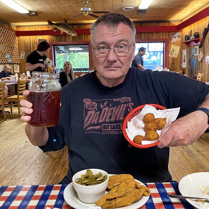The universal expression of a man who's found his happy place: sweet tea in one hand, hushpuppies in the other, catfish waiting patiently.