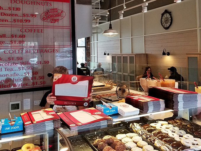 The display case—where doughnut dreams come true and diet plans go to die—staffed by the keepers of the sweet flame.