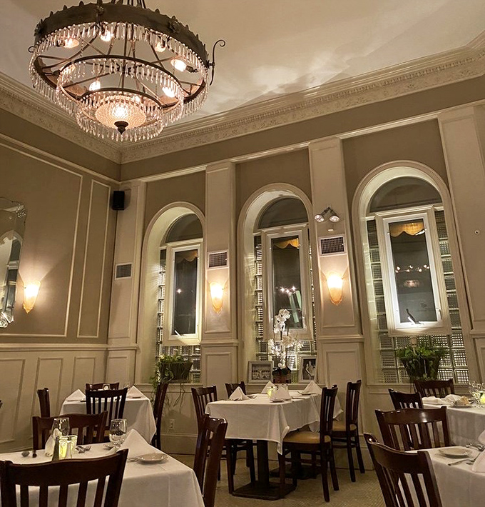 Evening light filters through arched windows, transforming this dining room into a cathedral of cuisine where conversations flow as smoothly as the house red.