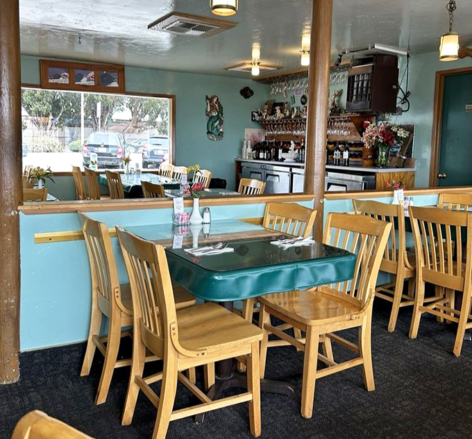 Teal tables and wooden chairs create that perfect "you're definitely at the coast" atmosphere. It's like sitting in a stylish fisherman's living room.