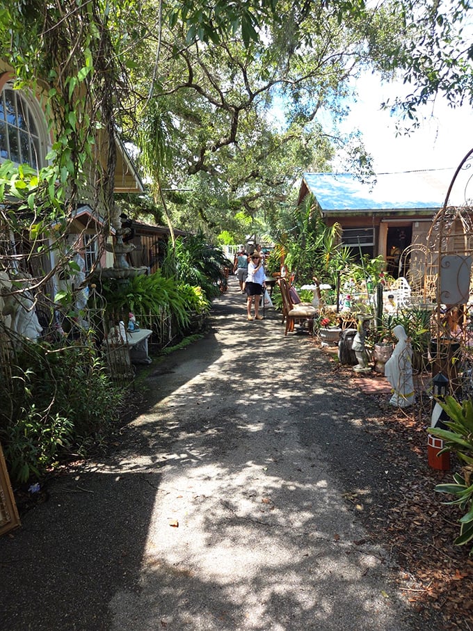 Nature and commerce blend seamlessly in this shaded pathway, where garden art and potted treasures create a botanical treasure hunt.