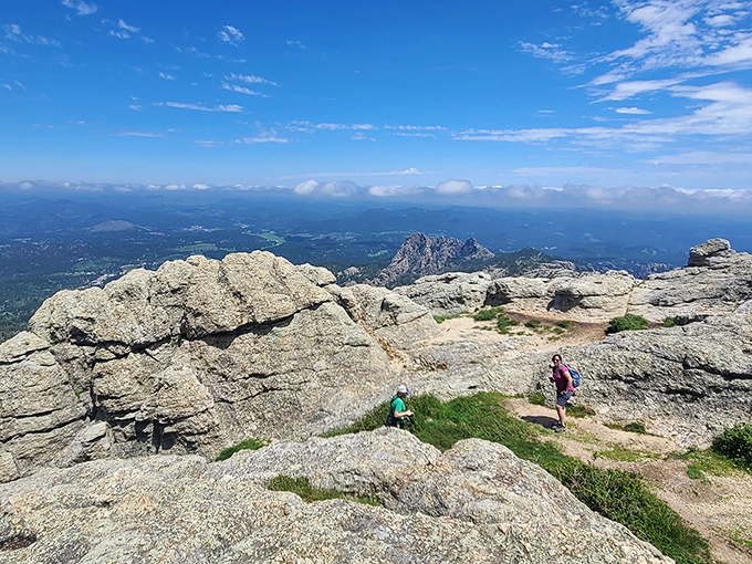 Hikers at the summit discovering that nature's version of a penthouse view requires more effort but delivers better satisfaction.
