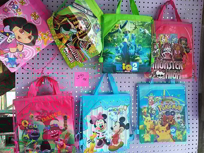 Childhood nostalgia hangs in neat rows. These cartoon-adorned bags would have been the envy of every school cafeteria in my day.