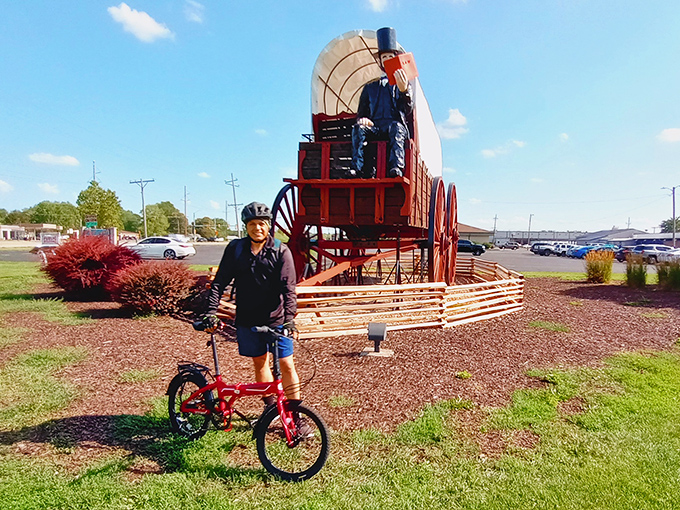 Size matters! This cyclist provides perfect scale for the mammoth wagon&mdash;it's like parking your bike next to a wooden whale beached on Route 66.