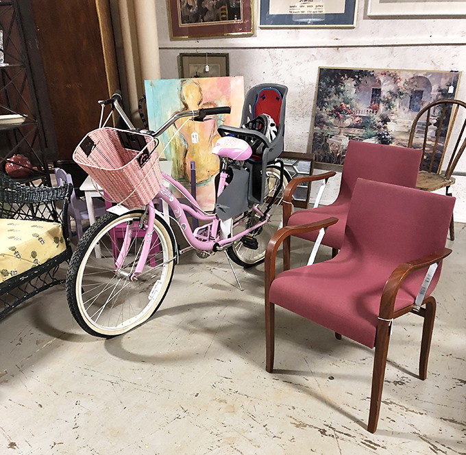 A pink bicycle that's basically screaming "Audrey Hepburn movie scene," parked next to chairs that would make any waiting room feel like a mid-century dream.