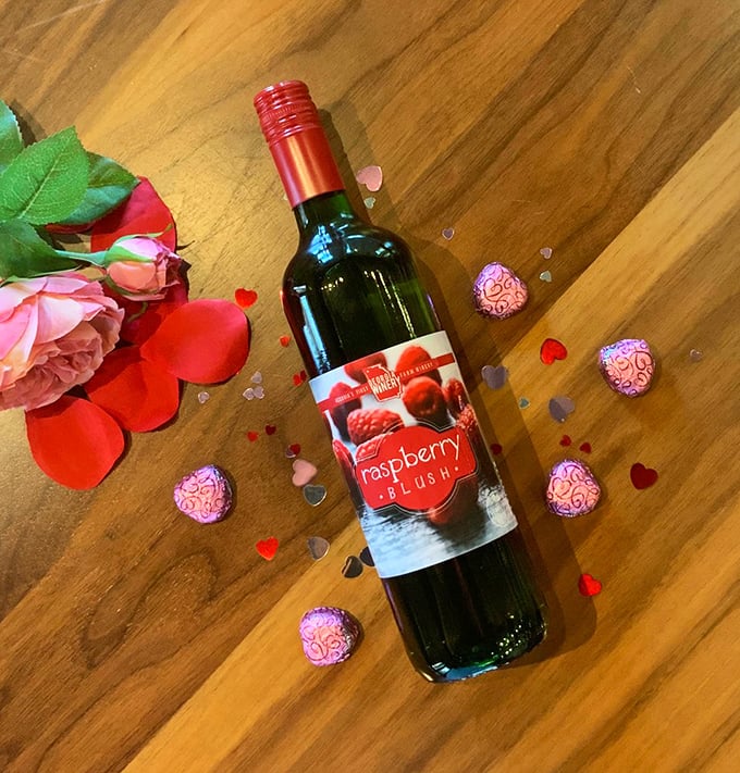 Raspberry Blush wine surrounded by Valentine's decorations &ndash; romance in a bottle, no reservation required.