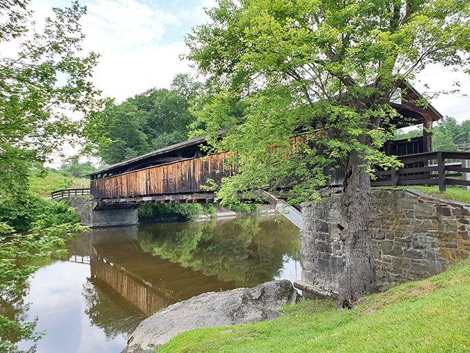 The stone abutments anchor this wooden marvel to earth, a marriage of materials that has withstood countless seasons.