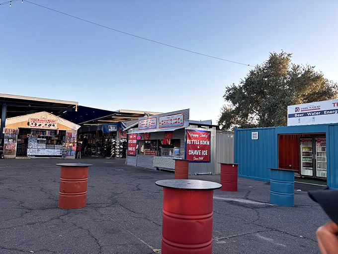 The swap meet's outdoor marketplace at dusk, where colorful barrels serve as impromptu tables and the real magic happens after the sun starts setting.