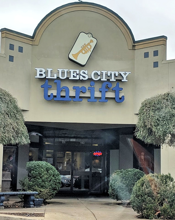 Blues City Thrift's welcoming entrance features their musical trumpet logo, lush greenery, and an inviting pathway to bargain treasures inside.