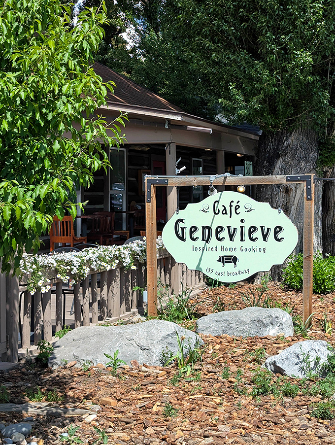 Cafe Genevieve's charming sign nestled among rocks and flowers looks like it belongs in a storybook about the perfect breakfast spot.