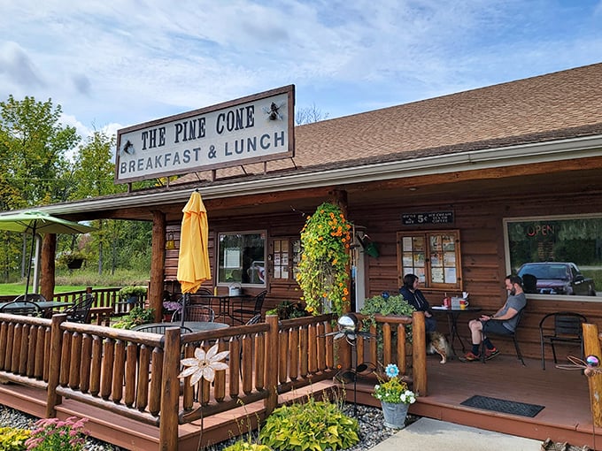 The Pine Cone's rustic log cabin exterior promises northwoods comfort in sandwich form, complete with porch seating for soaking in nature.