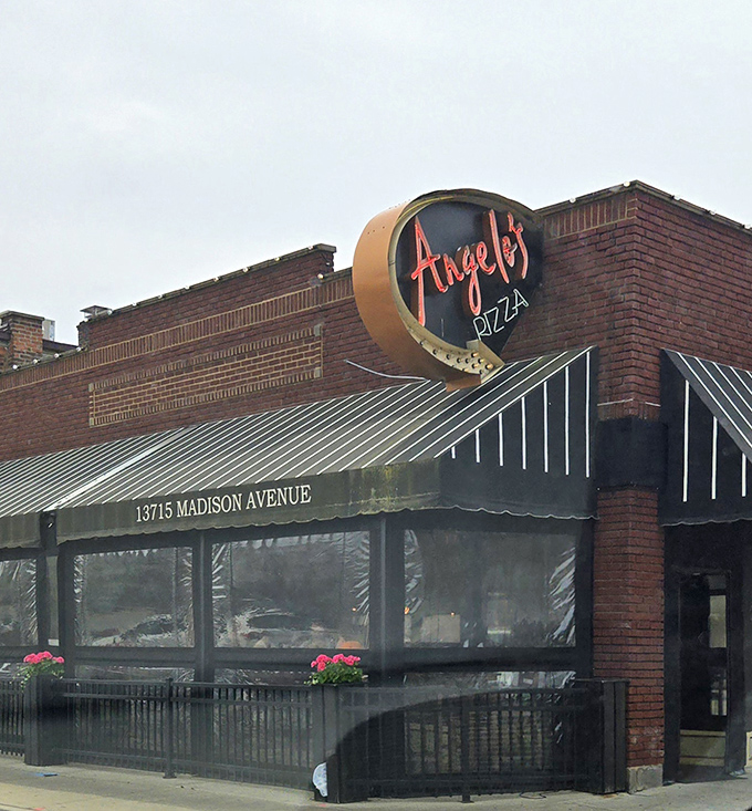 The circular sign at Angelo's Pizza promises round perfection inside. Spoiler alert: it delivers on that promise!