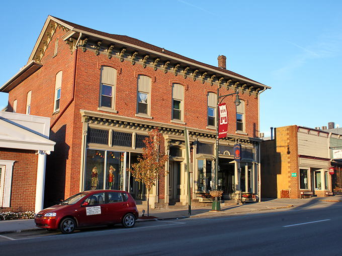 Golden hour light warms the ornate brick facade of a historic downtown building, casting a rich glow over the storefront and the quiet street below a clear blue sky.
