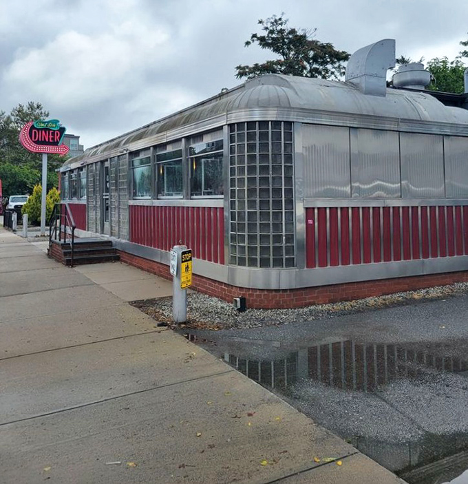 Rain-slicked pavement reflects West Side Diner's vintage charm&mdash;a stainless steel sanctuary where comfort food awaits, regardless of weather.