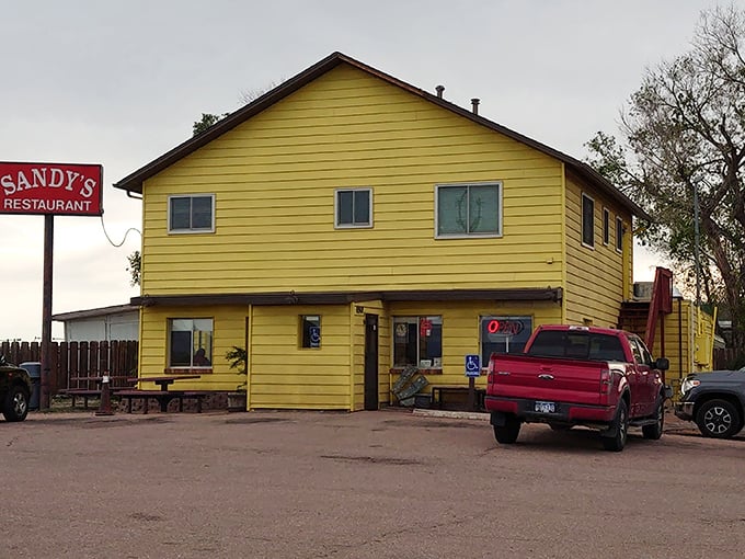 The bright yellow exterior of Sandy's Restaurant stands as an unassuming beacon for hungry travelers seeking authentic comfort food in Colorado Springs.