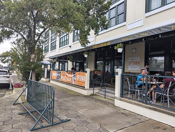 The welcoming storefront of Uptown Kitchen & Bar invites you in with its cheerful yellow signage and cozy patio seating. Jacksonville's hidden gem awaits.